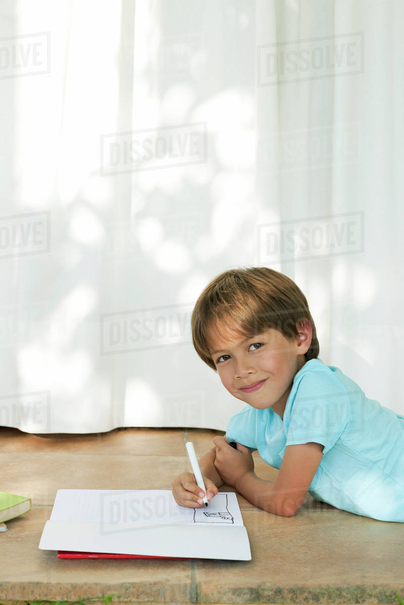 Boy lying on ground, drawing in notebook - Royalty-free Stock Photo ...