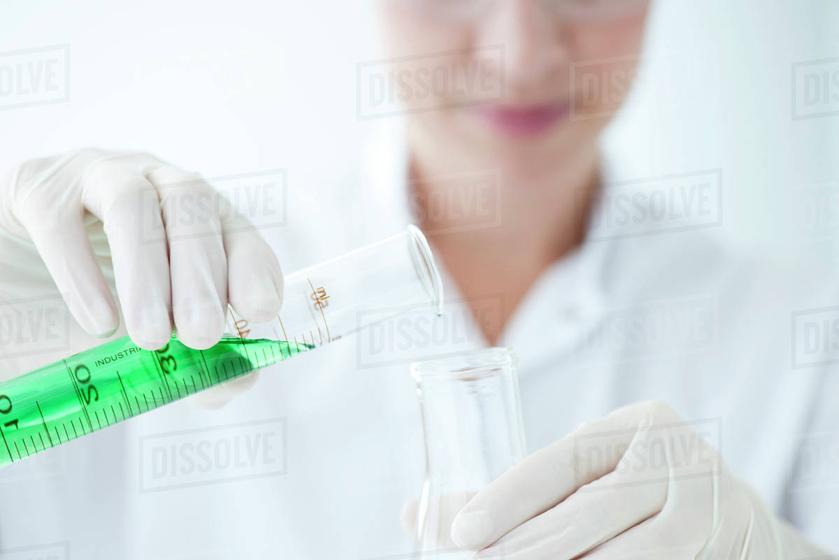 Scientist pouring liquid from graduated cylinder to test tube - Stock ...