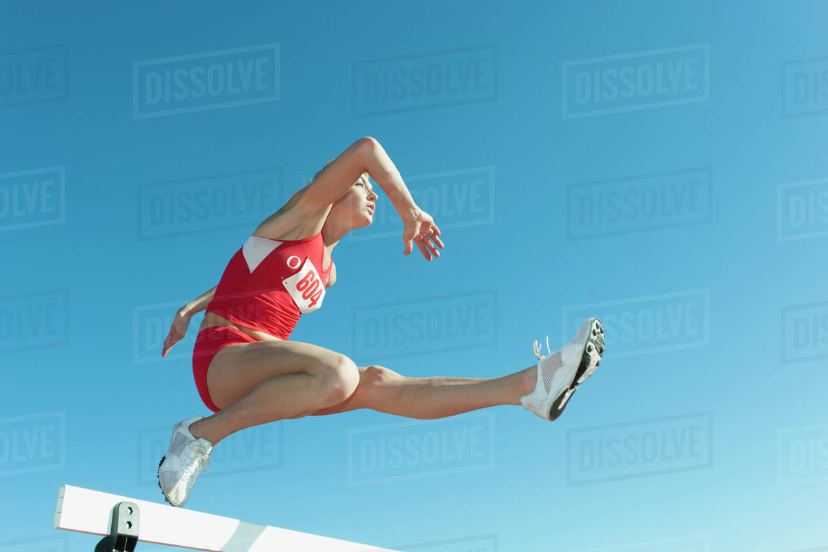 Famale athlete jumping over hurdle, low angle view - Royalty-free Stock ...