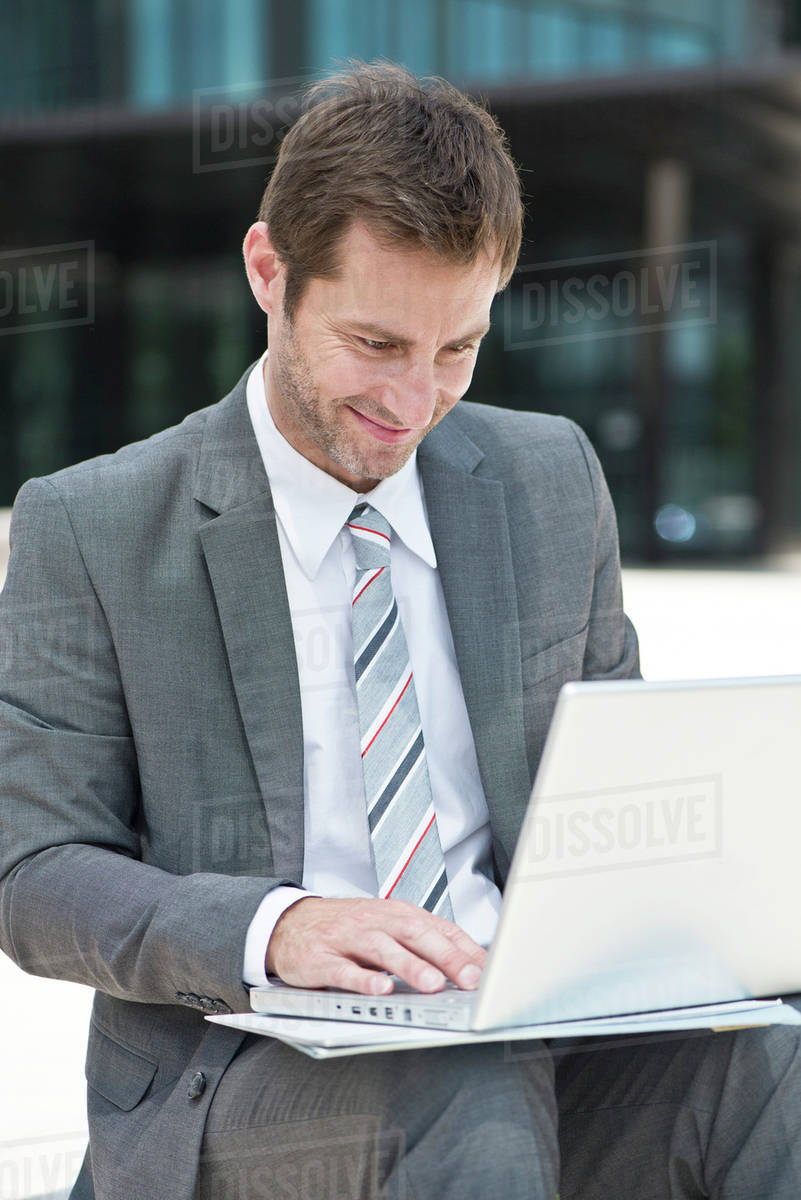 Businessman using laptop outdoors - Royalty-free Stock Photo | Dissolve