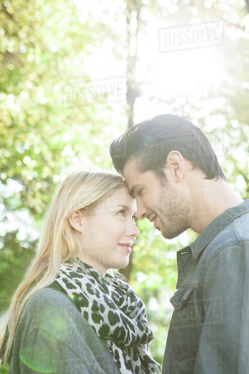Couple nuzzling each other outdoors - Stock Photo - Dissolve