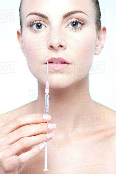 Woman holding up syringe - Royalty-free Stock Photo | Dissolve