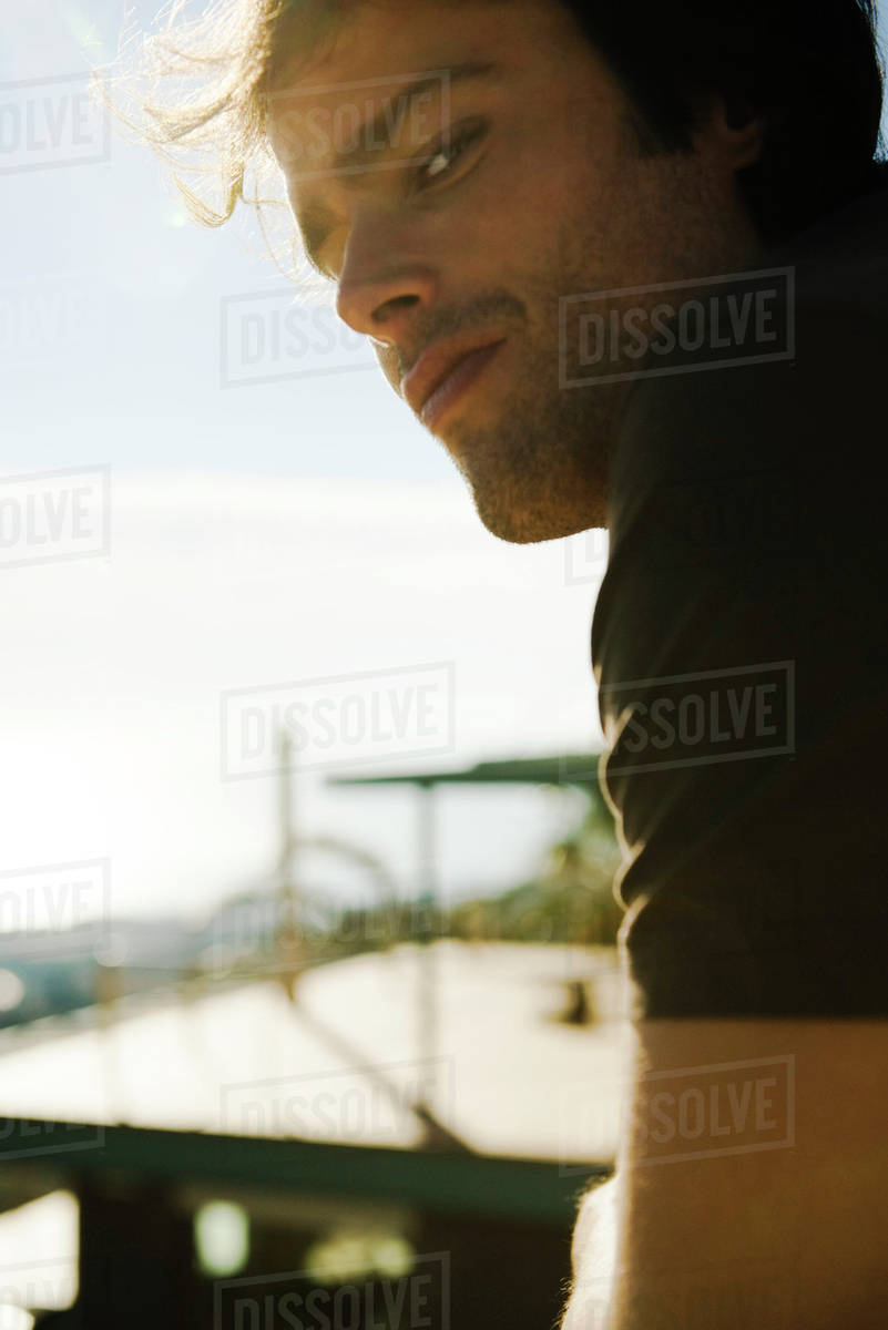 Man looking over shoulder at camera, portrait - Stock Photo - Dissolve
