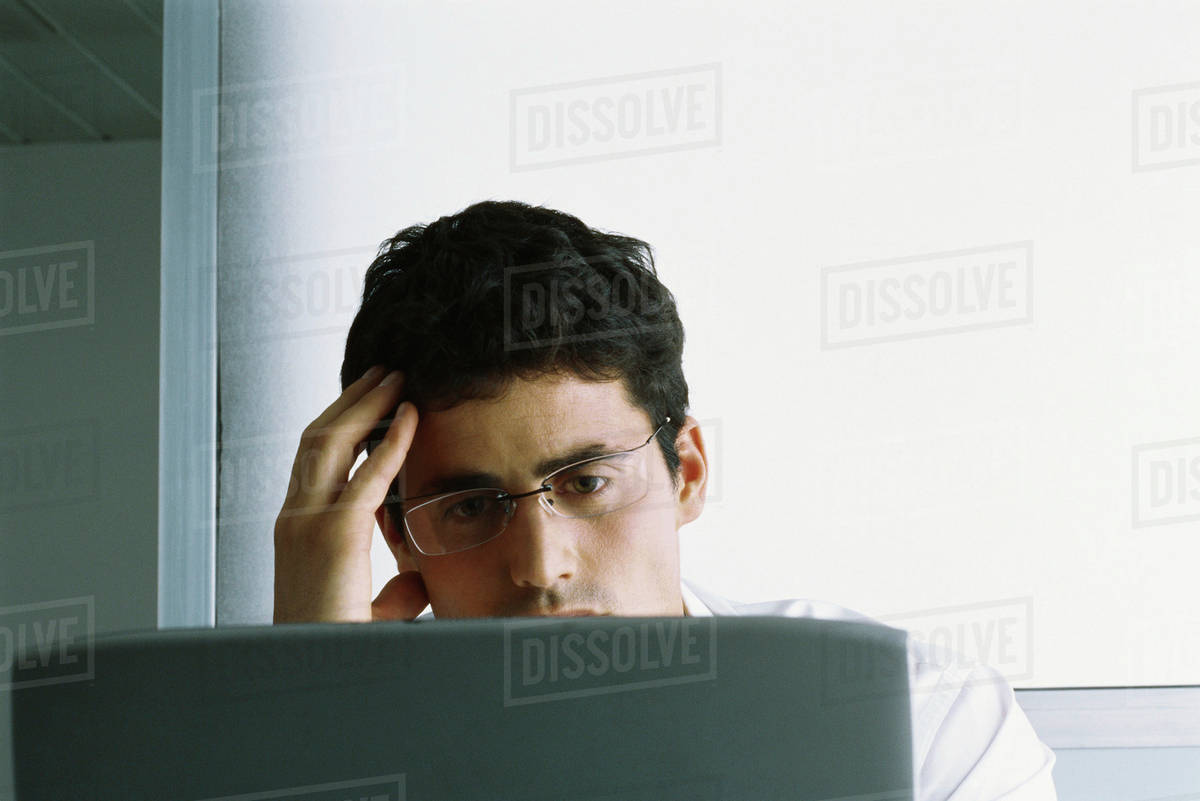 Man working on computer, holding head - Royalty-free Stock Photo | Dissolve