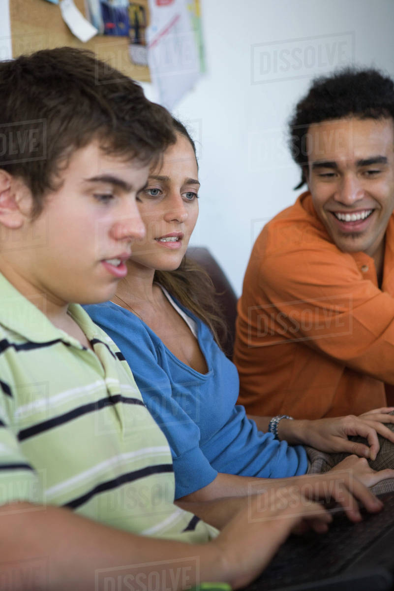 Male college student using laptop computer, classmates sitting ...