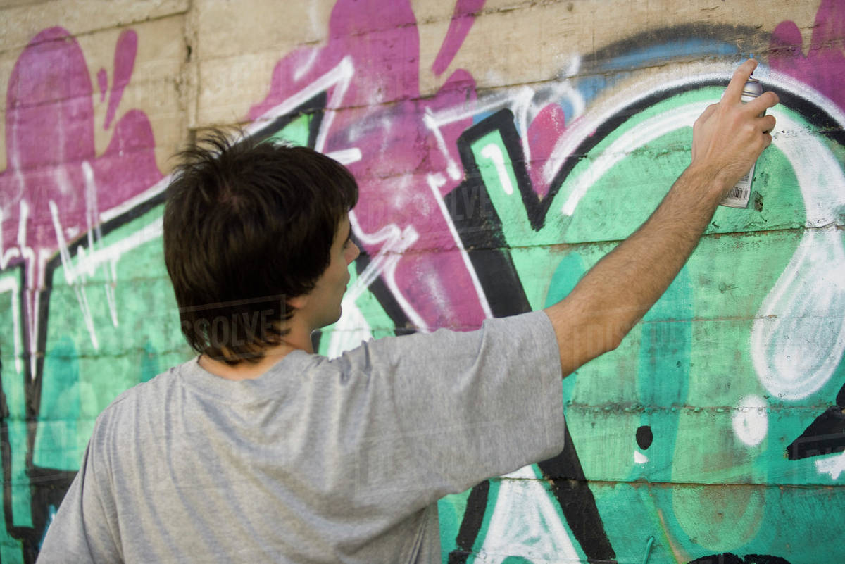 Young man spray painting graffiti mural - Royalty-free Stock Photo ...