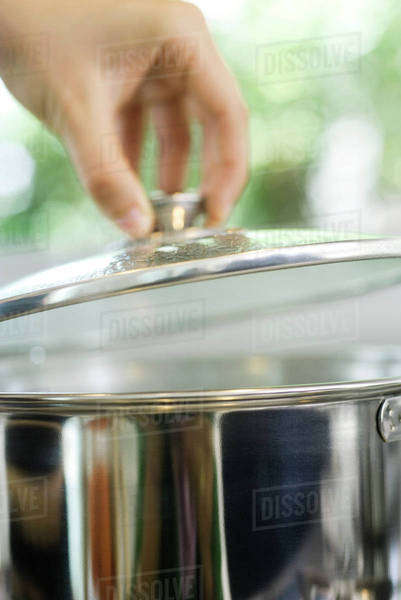 Person removing lid from cooking pot - Royalty-free Stock Photo | Dissolve