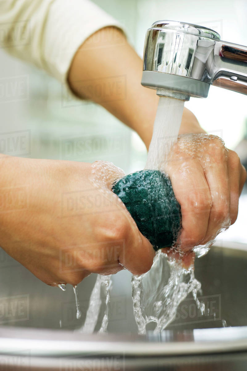 Person rinsing sponge under kitchen faucet - Royalty-free Stock Photo ...