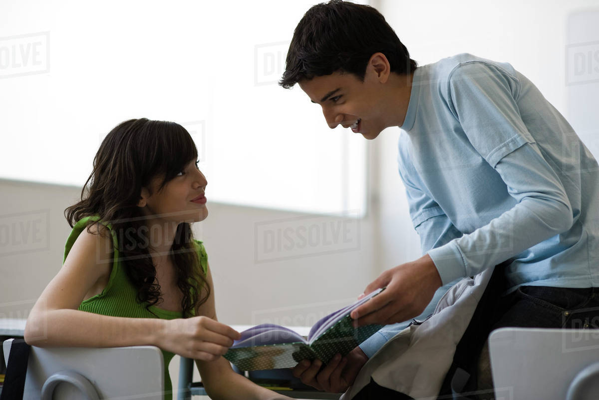 High school student showing book to classmate - Stock Photo - Dissolve