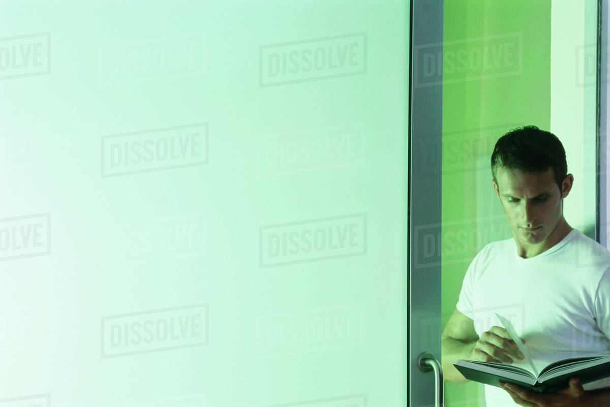 Man leaning in doorway, reading book - Royalty-free Stock Photo | Dissolve