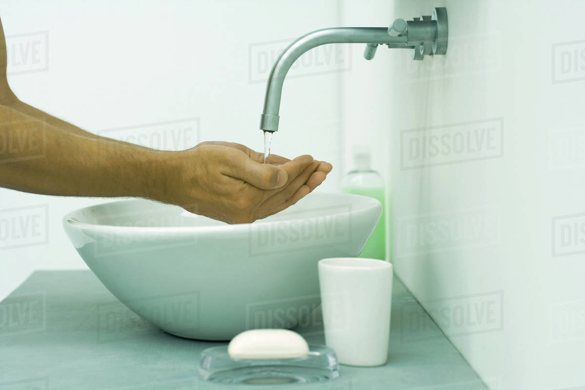 Man's hands under running water in bathroom sink, side view - Stock ...