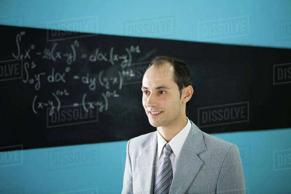 Man in suit looking away, smiling, mathematic equation on blackboard in ...