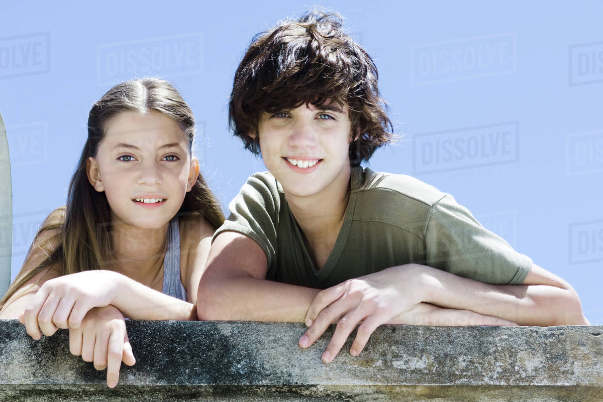 Two young friends standing side by side, smiling at camera, portrait ...