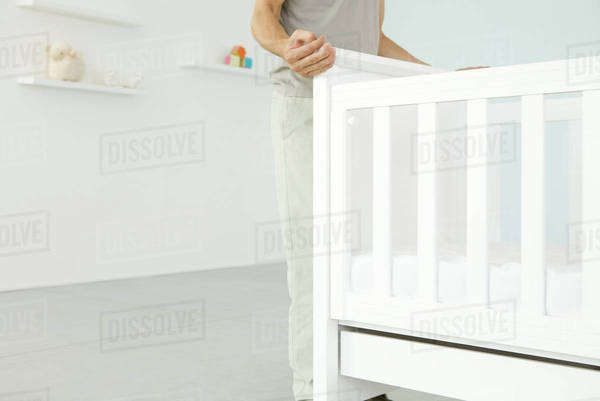Man standing beside crib in nursery, cropped view - Royalty-free Stock ...