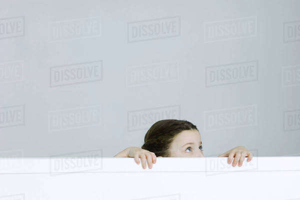 Little girl peeking over ledge - Royalty-free Stock Photo | Dissolve