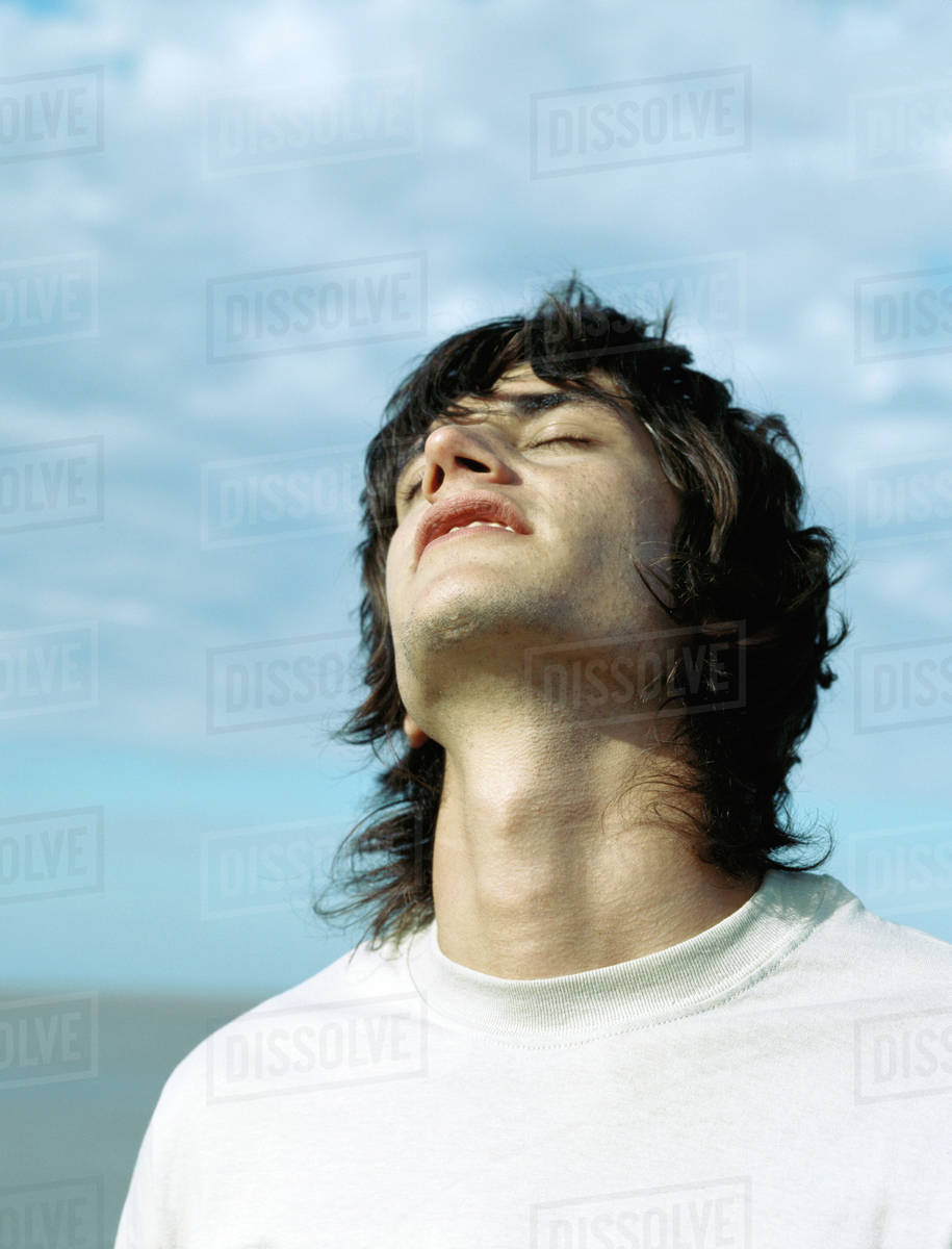 Man outdoors, leaning head back, eyes closed - Stock Photo - Dissolve
