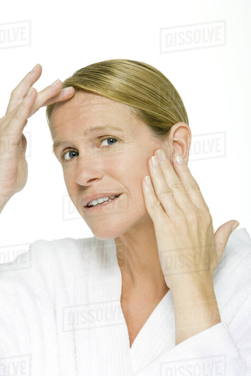 Woman touching forehead and cheek, close-up - Stock Photo - Dissolve