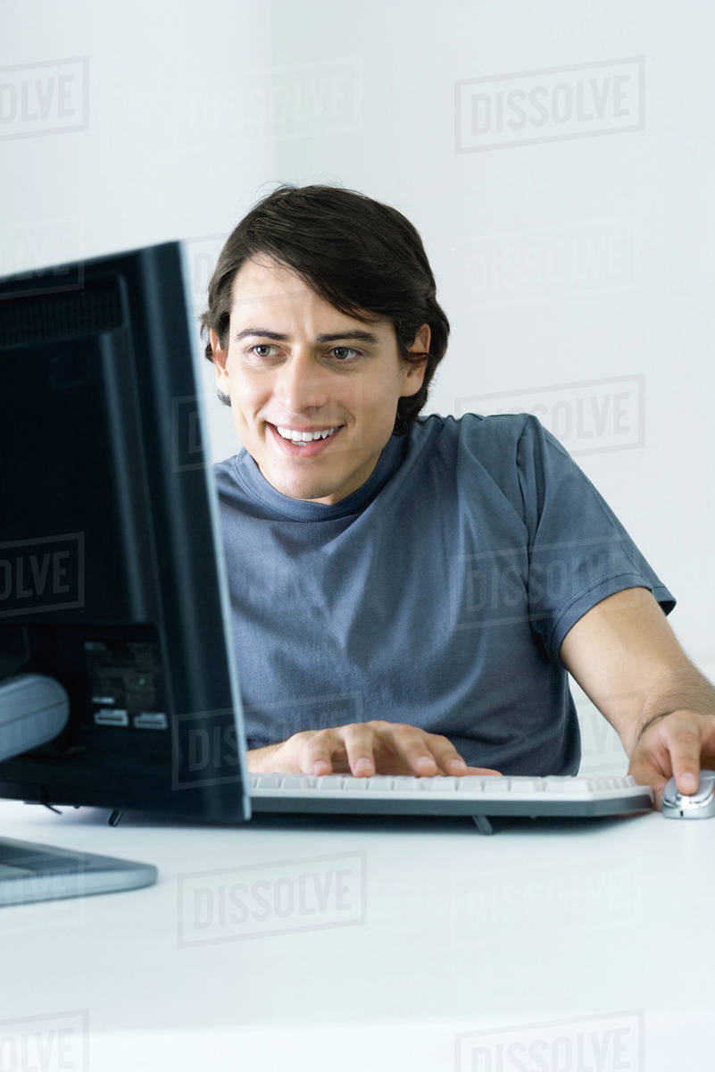 Man using desktop computer, smiling - Royalty-free Stock Photo | Dissolve