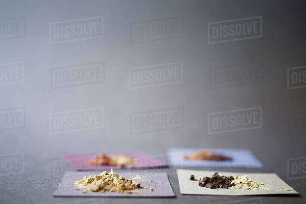 Four squares of paper holding different colored powders - Stock Photo ...