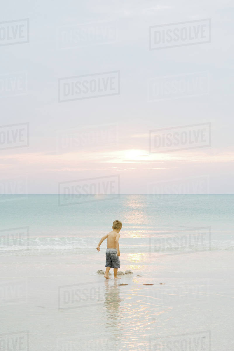 Little boy playing on beach at sunset, rear view, full length - Stock ...
