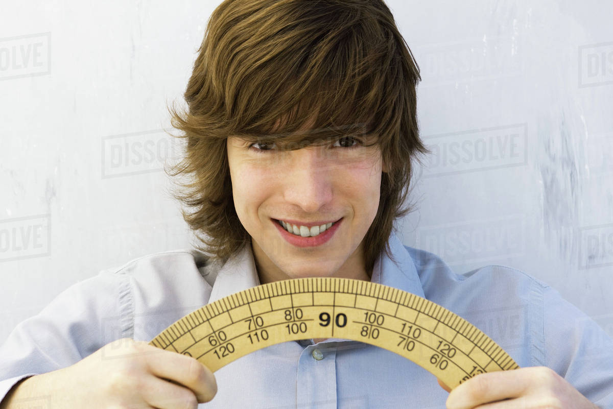 Young man holding protractor in both hands, smiling at camera - Stock ...