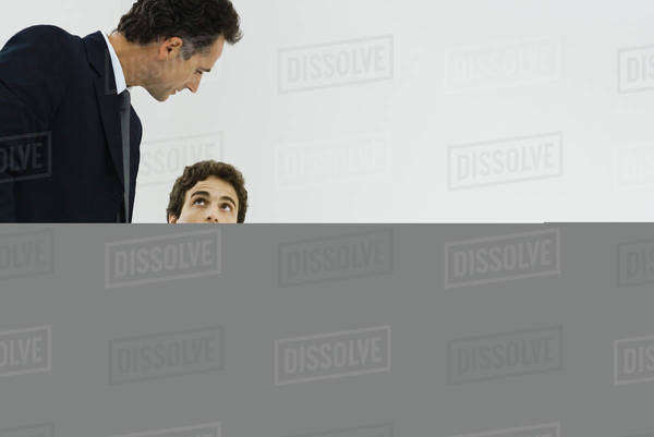 Boss looking over employee's shoulder, employee holding hand over ...