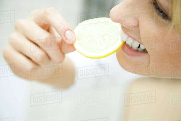Woman biting into slice of lemon, smiling, close up - Stock Photo ...