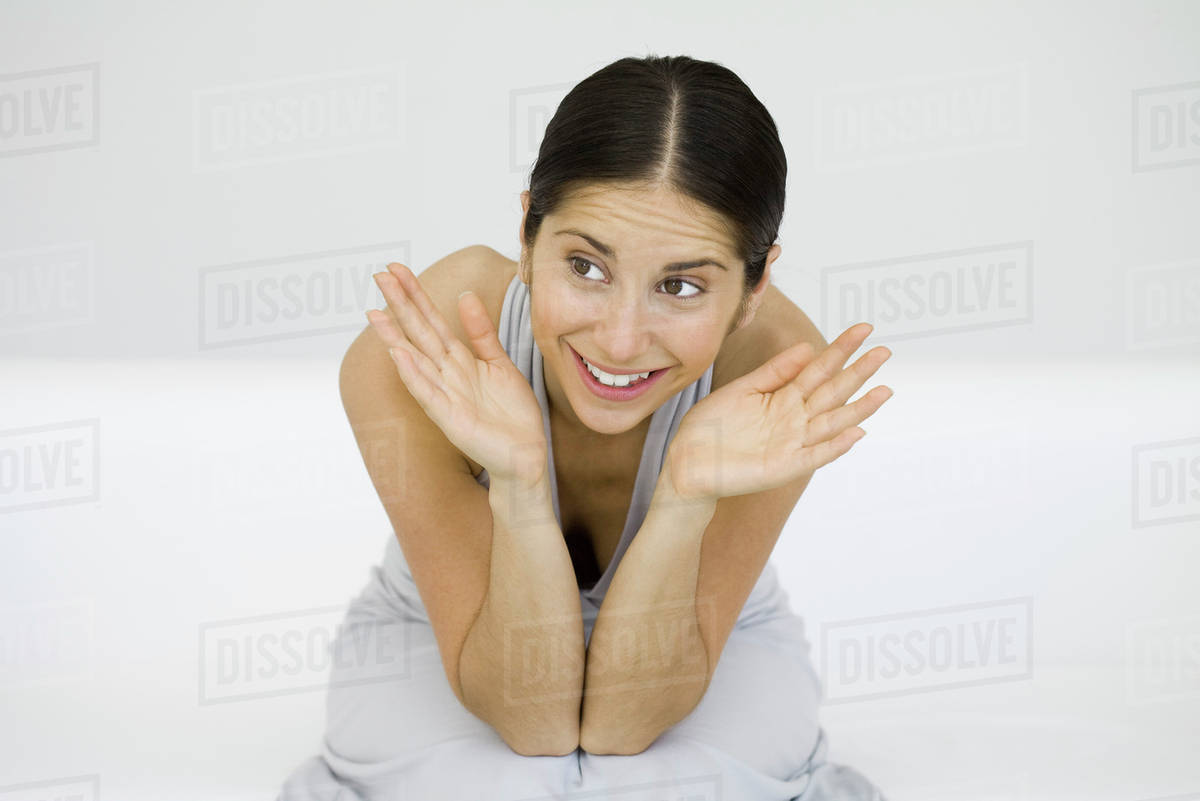 Woman leaning on elbows, hands open by face, smiling, looking away ...