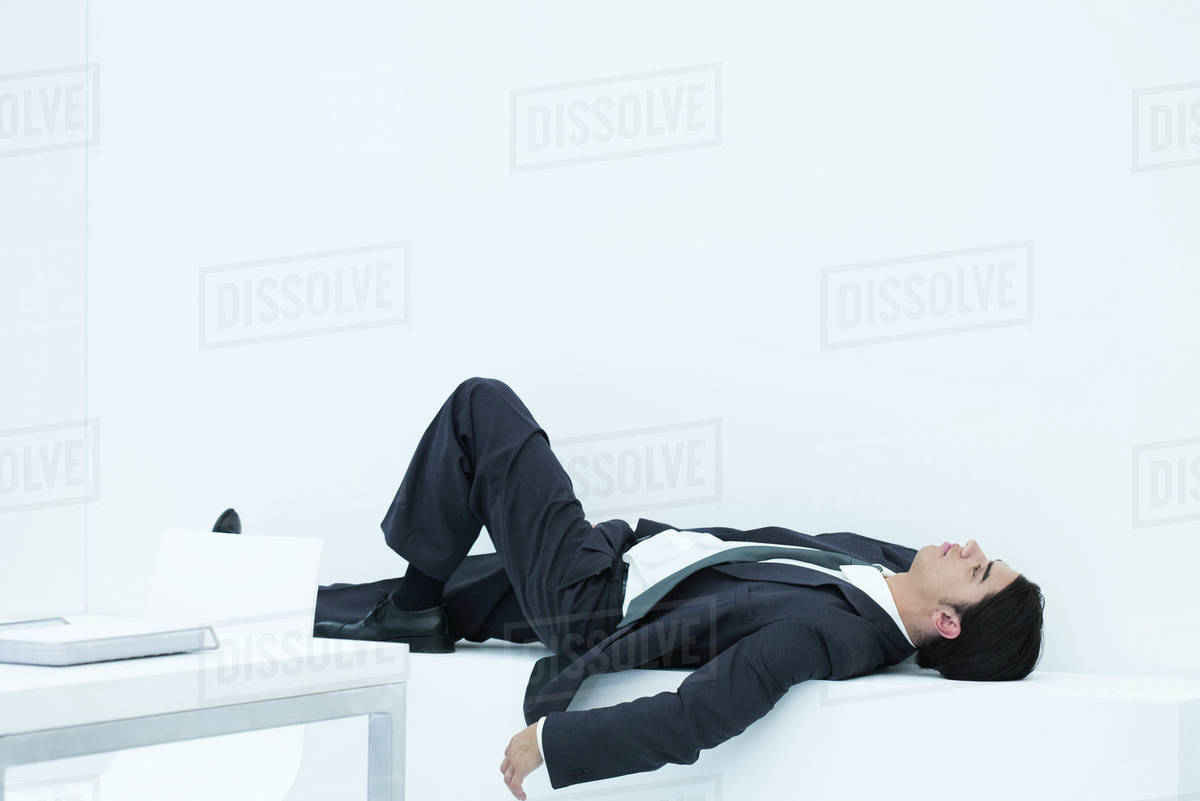 Businessman lying down on ledge in office - Royalty-free Stock Photo ...