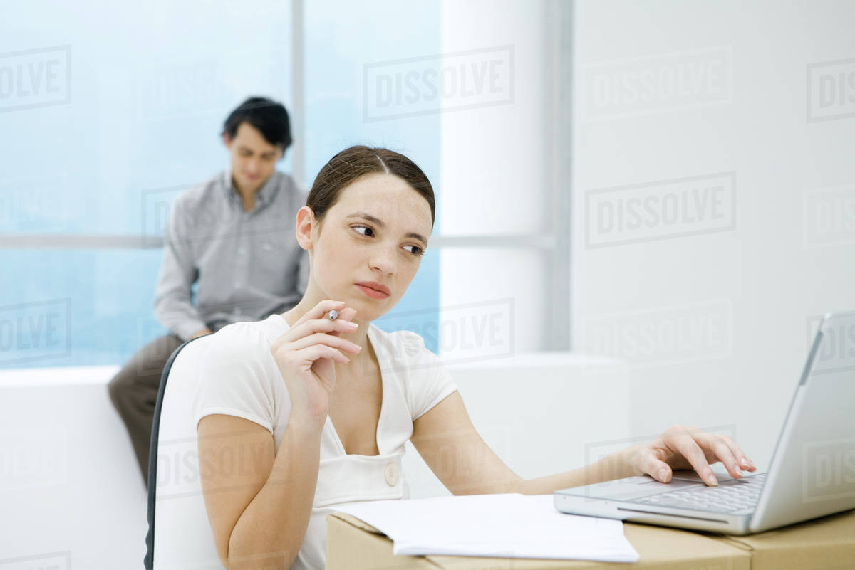 Young woman sitting at makeshift desk, using laptop computer - Stock ...