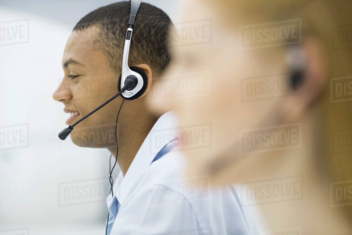 Telemarketers wearing headsets, profile, focus on background - Royalty ...