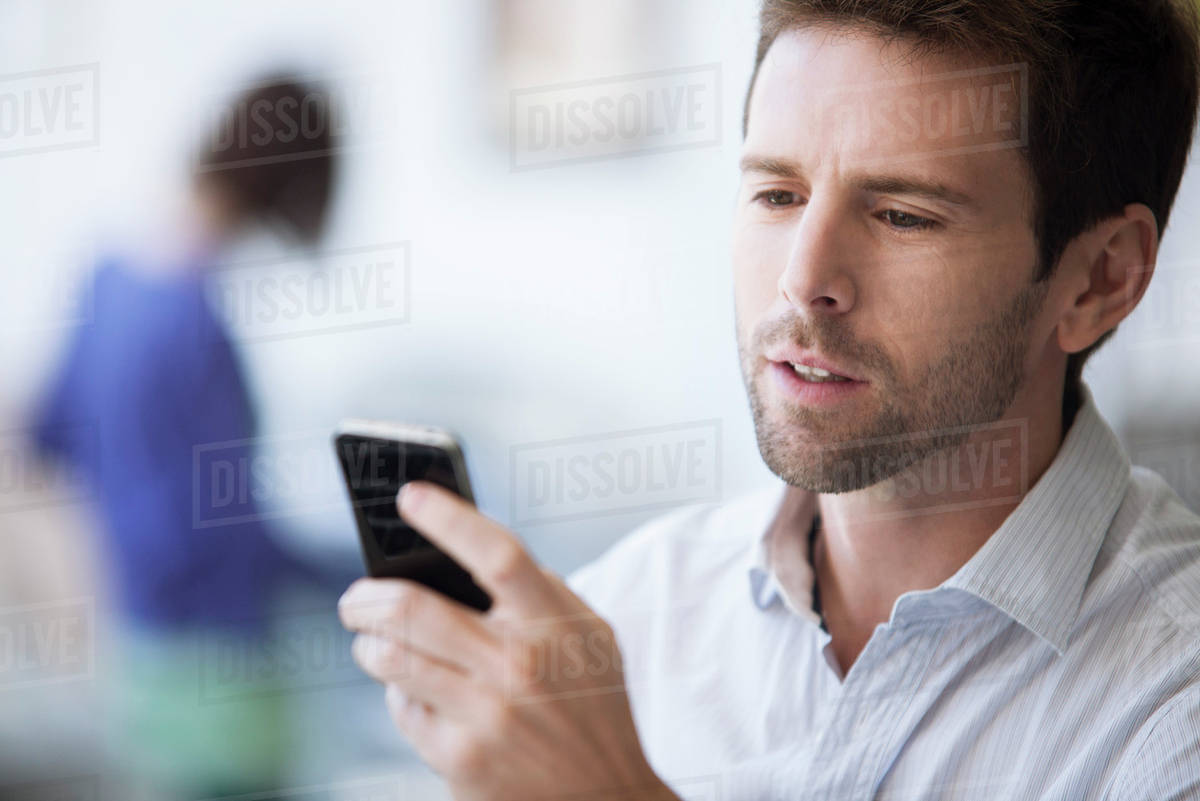 Mid-adult man checking cell phone - Royalty-free Stock Photo | Dissolve