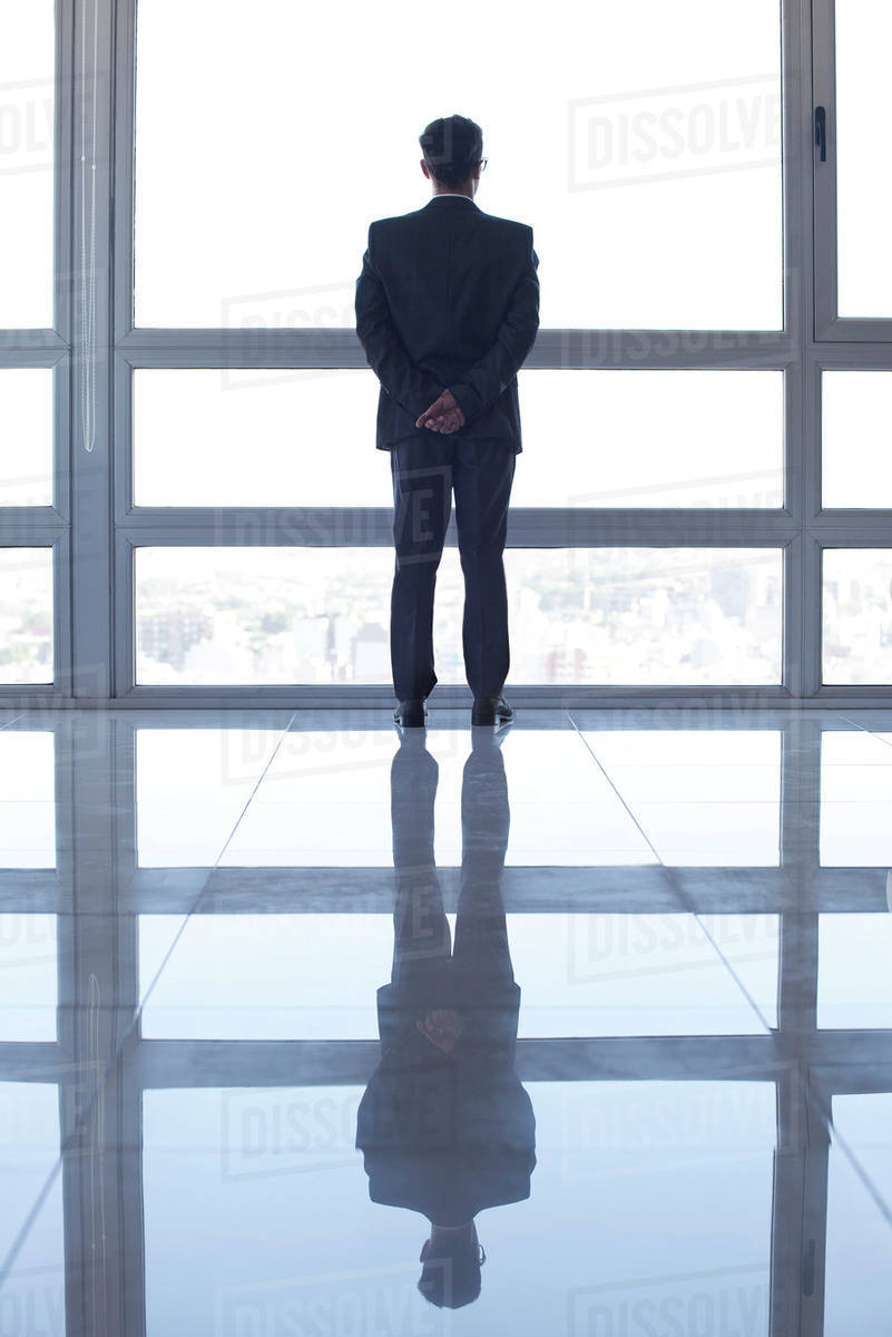 Businessman looking out high rise window at view of city below at ...