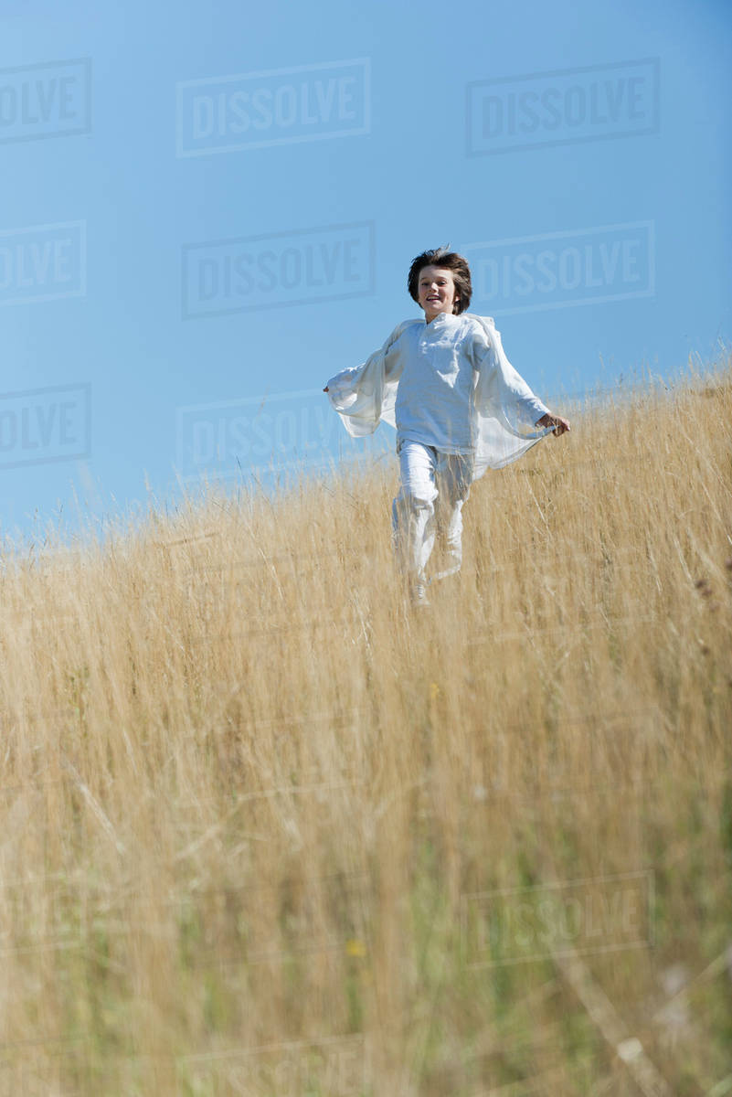 Boy running through tall grass - Royalty-free Stock Photo | Dissolve
