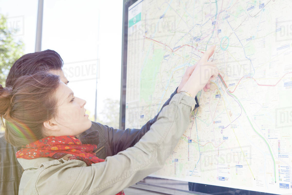 Tourist couple looking at outdoor city map at tourist information ...