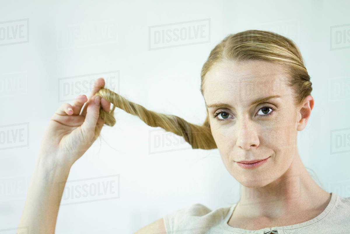 Woman twisting hair, smiling at camera, portrait - Stock Photo - Dissolve