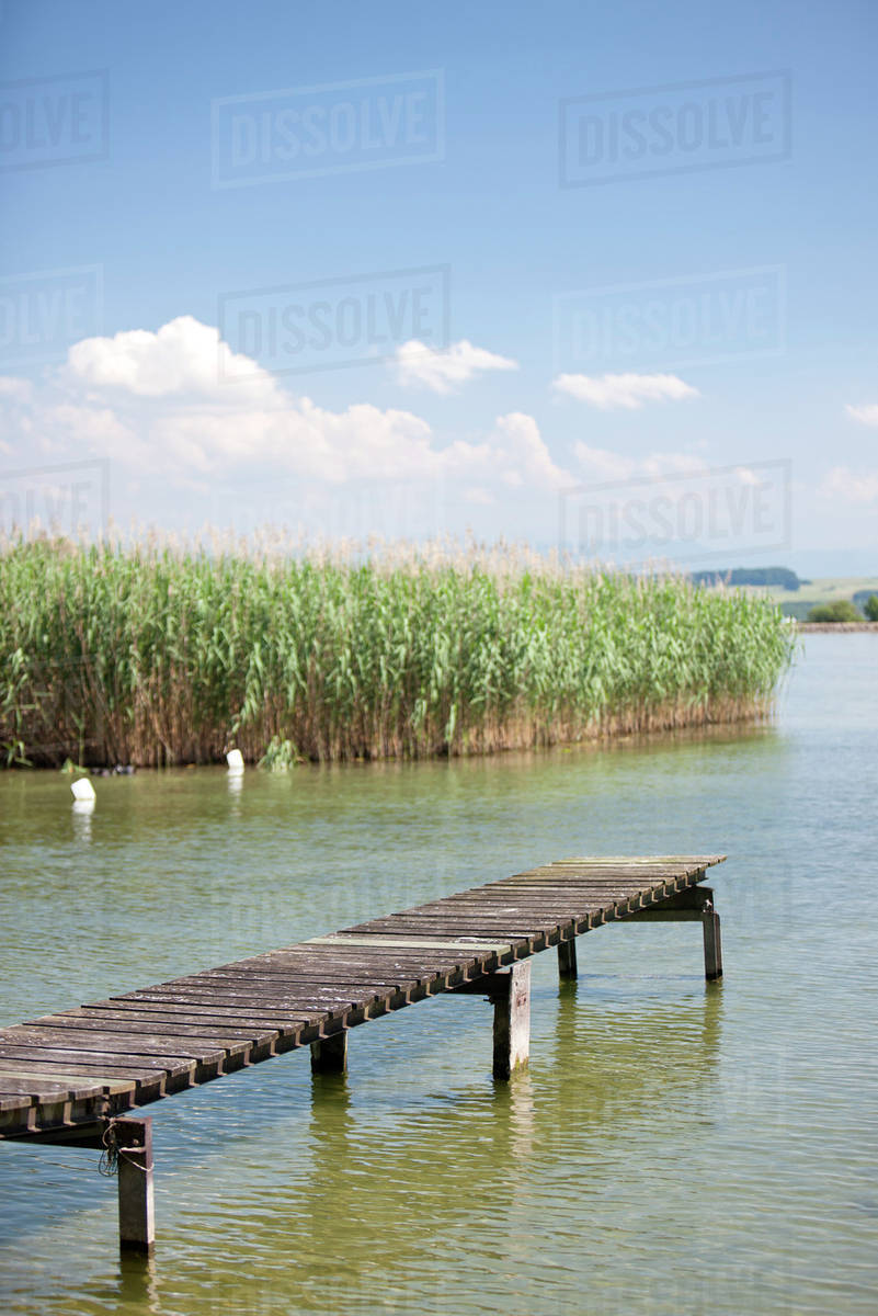 Pier over water, embankment in background - Stock Photo - Dissolve