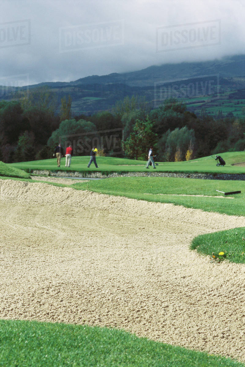 Golfers on golf course, sand trap in foreground - Royalty-free Stock ...