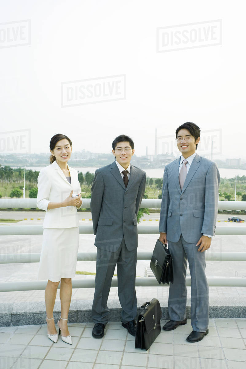 Three business executives standing by railing, looking at camera, full ...