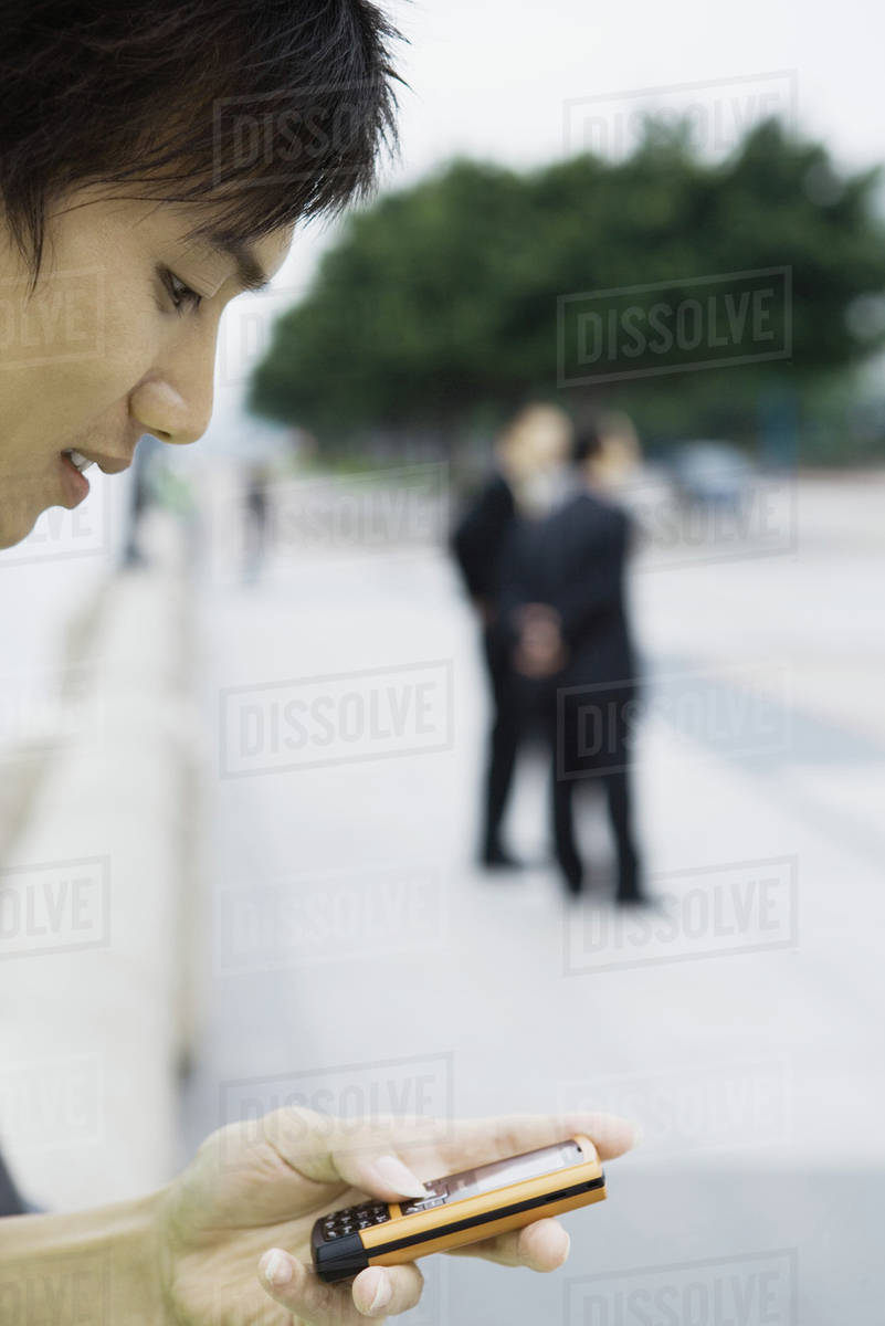 Young man looking at cell phone - Royalty-free Stock Photo | Dissolve