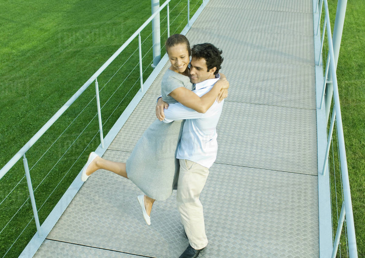 Couple on walkway, man spinning woman around in his arms - Royalty-free ...