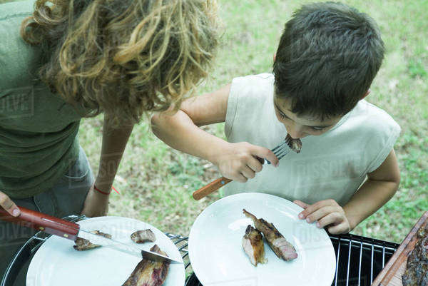 Two boys eating grilled meat - Royalty-free Stock Photo | Dissolve