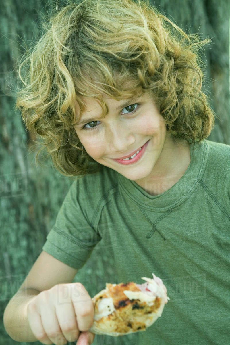 Boy holding grilled chicken leg, smiling at camera, portrait - Royalty ...