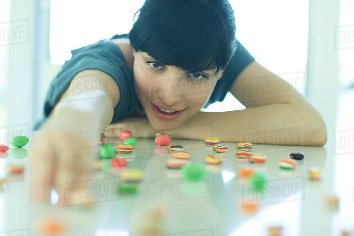 Table spread with candy, woman resting head on arms, reaching for piece ...