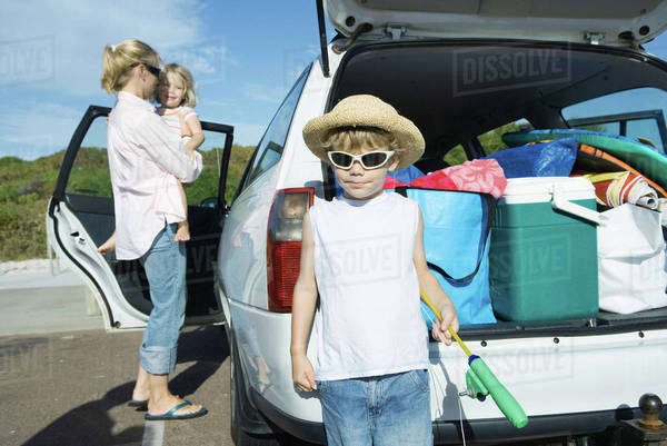 Boy standing in front of loaded car trunk - Stock Photo - Dissolve