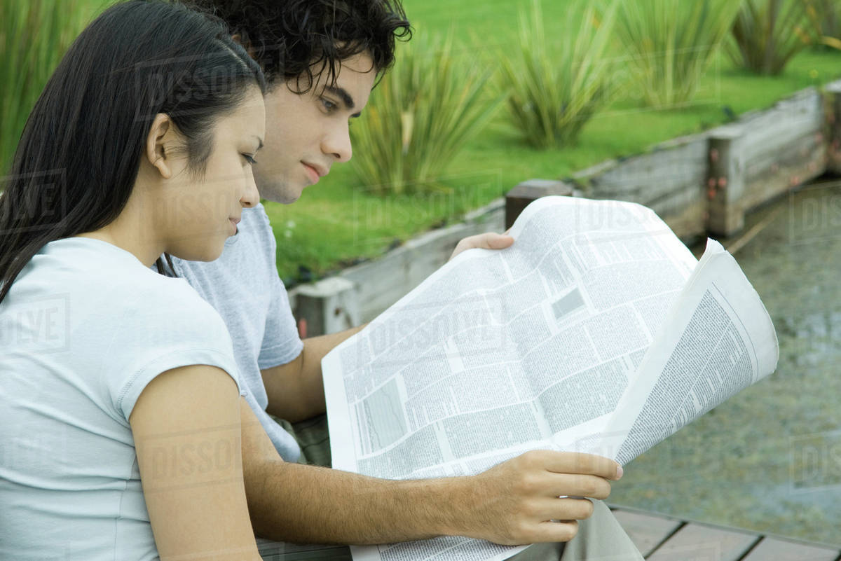 Young couple reading newspaper together outdoors - Royalty-free Stock ...