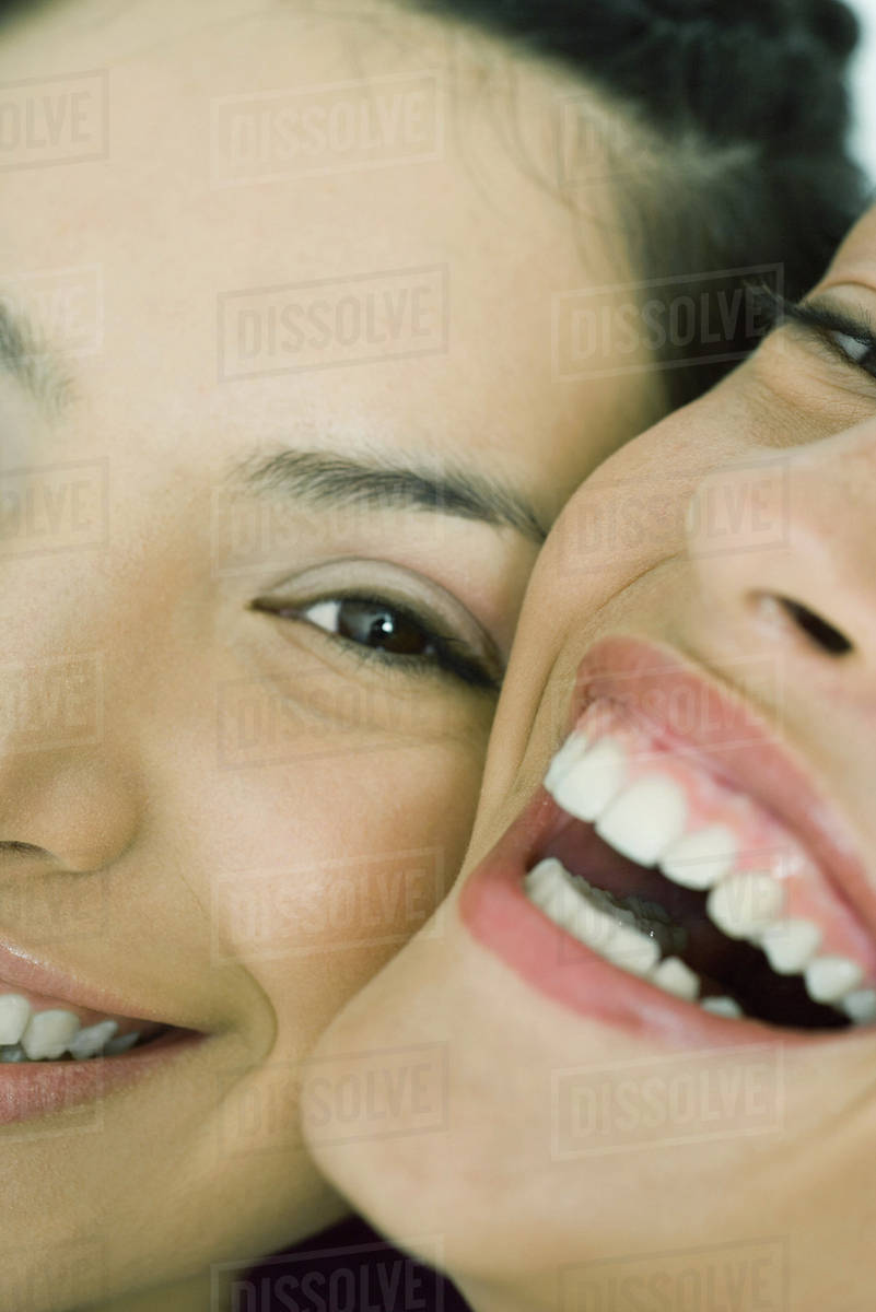 Cropped view of two young friends smiling at camera, cheek to cheek ...
