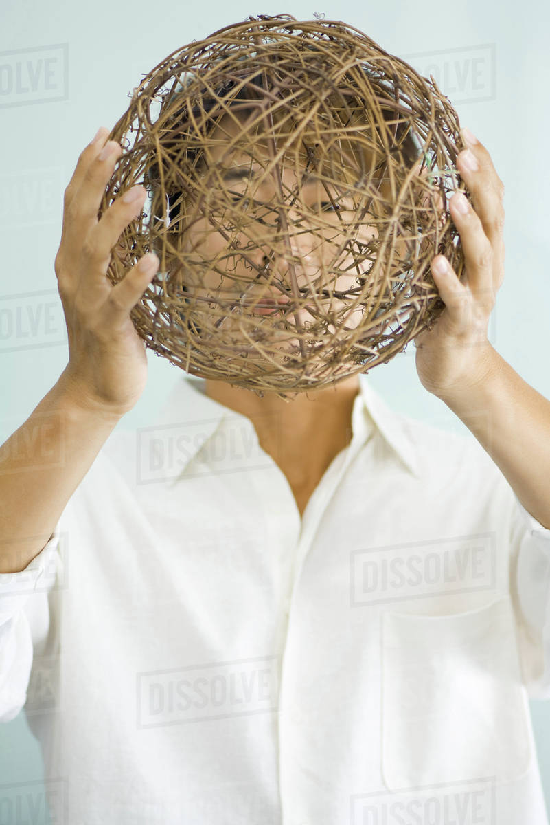 Man holding sphere in front of face - Stock Photo - Dissolve