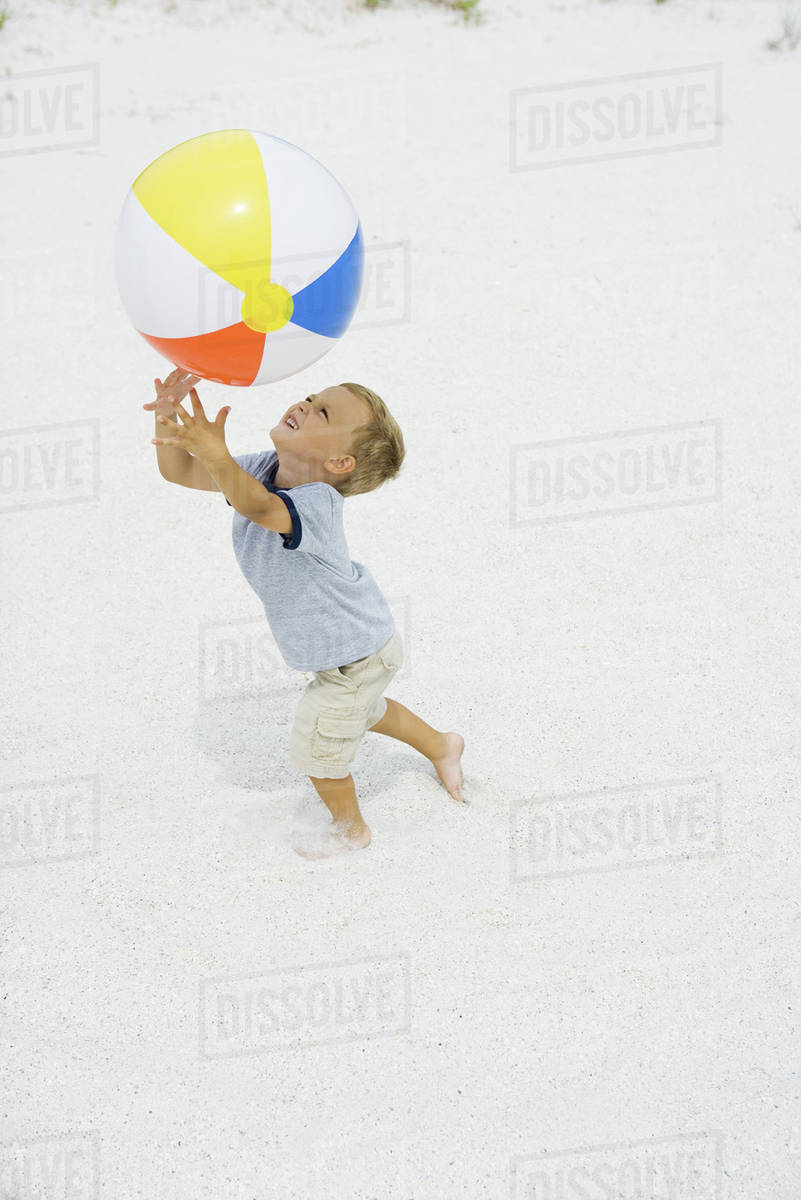 Young boy catching beach ball, arms raised, side view - Royalty-free ...