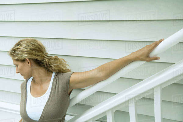 Woman leaning against railing, looking away - Stock Photo - Dissolve